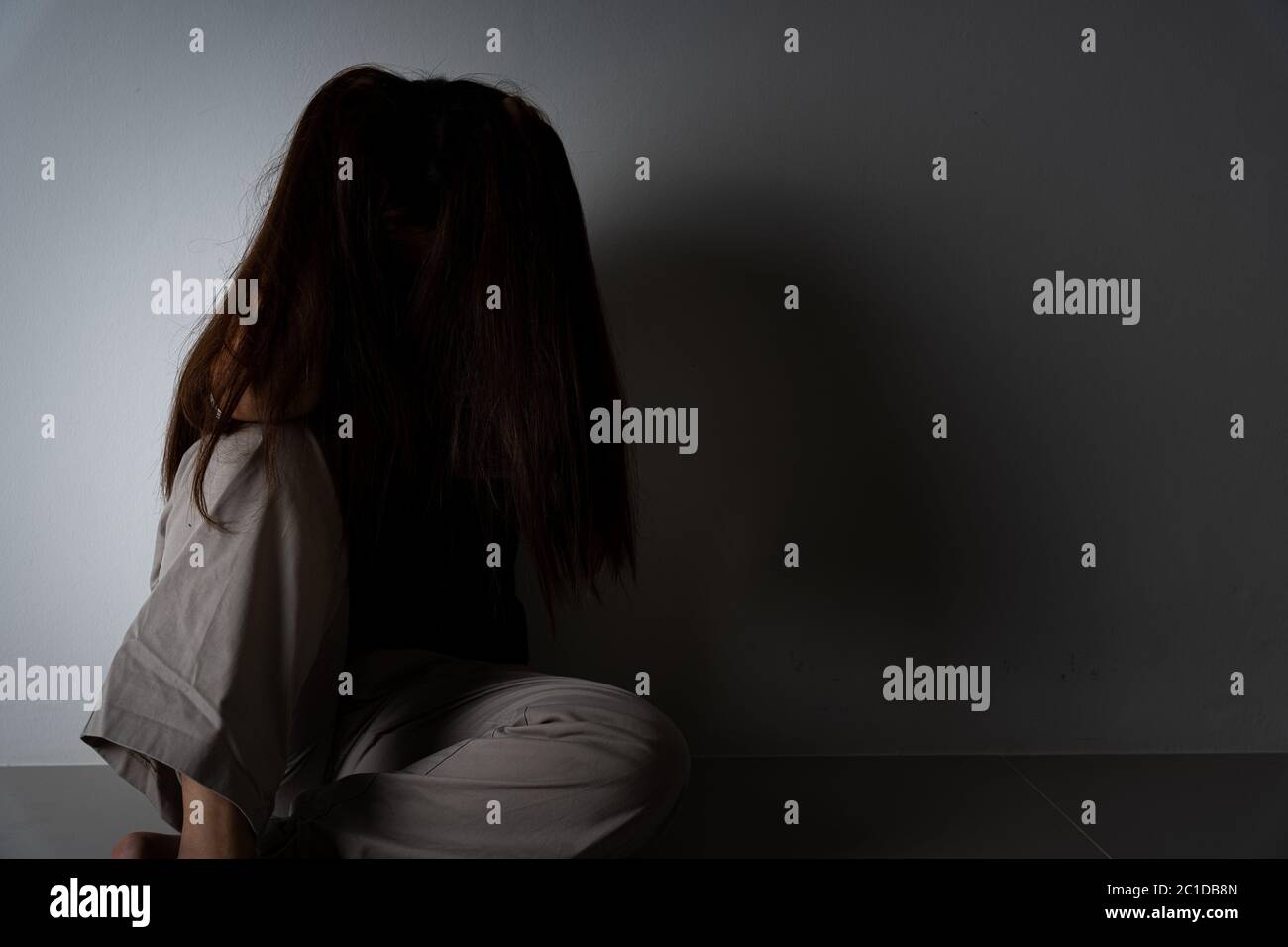 sad woman hug her knee and cry sitting alone in a dark room. Depression ...