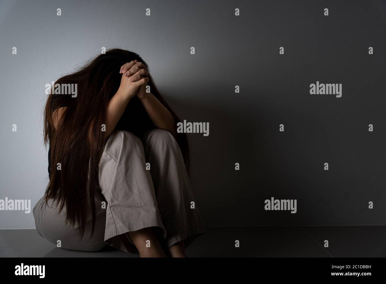 sad woman hug her knee and cry sitting alone in a dark room. Depression ...