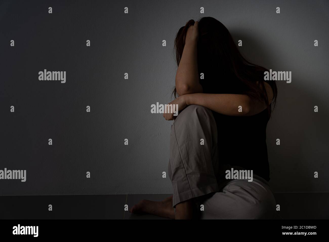 sad woman hug her knee and cry sitting alone in a dark room. Depression ...