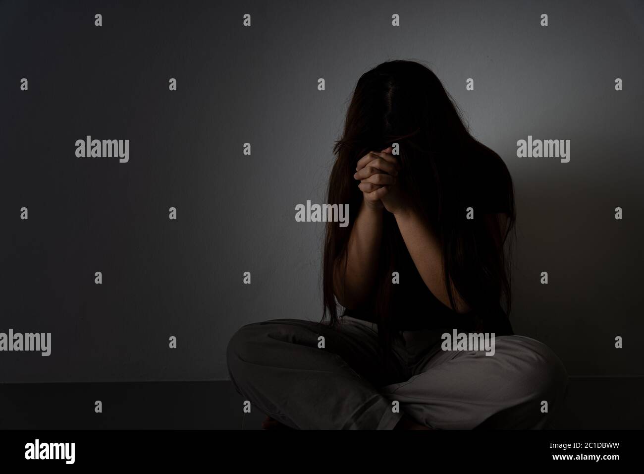 sad woman hug her knee and cry sitting alone in a dark room. Depression ...