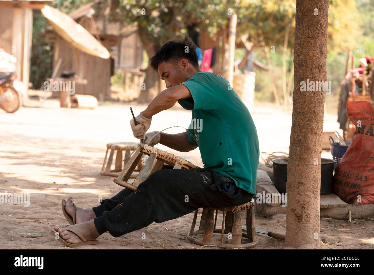 An indigenous, ethnic Akha man making stools in his village in Luang ...
