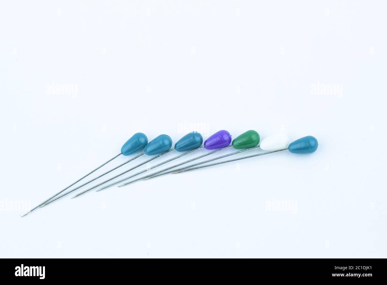 Six different colored brooches pin placed beside each other on a white ...