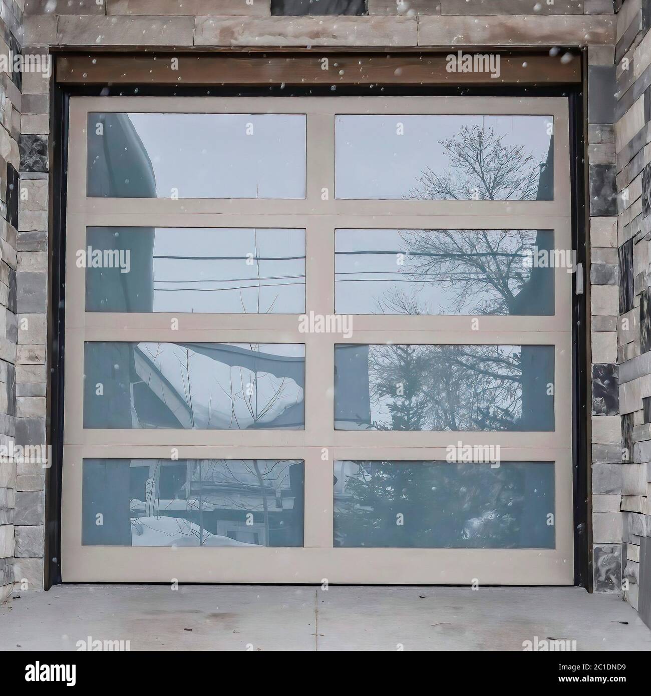 Square frame Snow falling down on home with glass panel garage door and ...