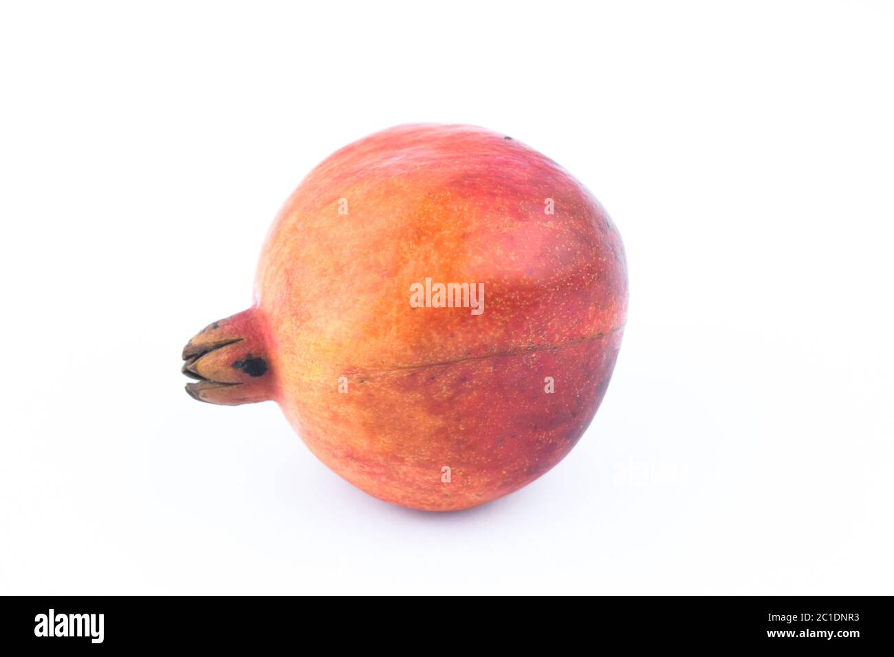 A light red colored pomegranate fruit placed on a white isolated paper ...