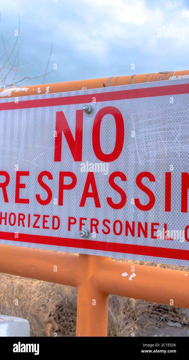 Vertical No Trespassing sign on an old metal fence against distant lake ...