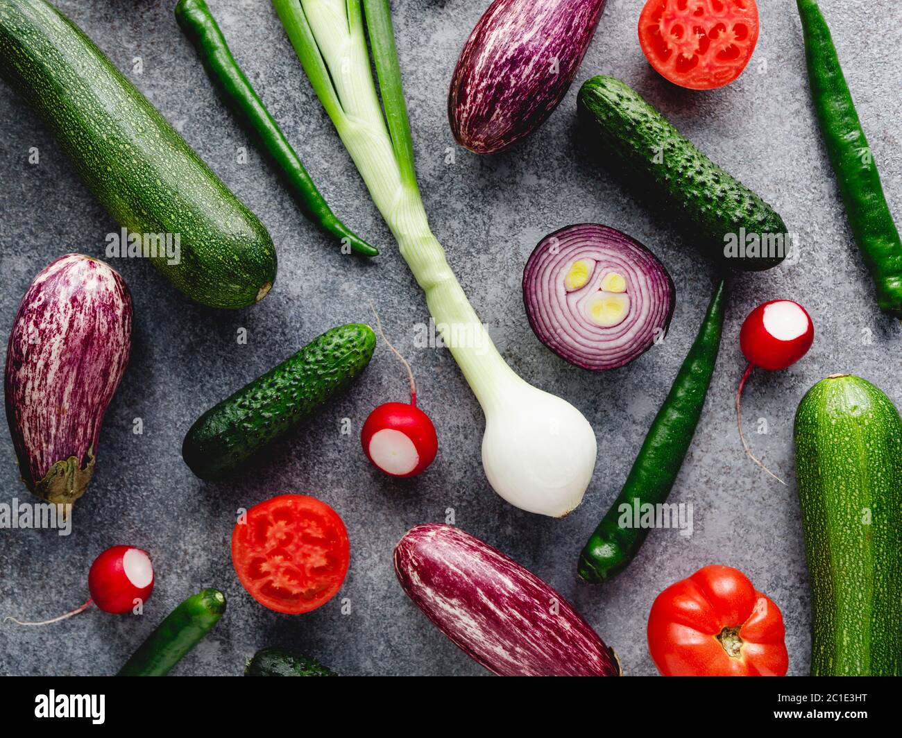Colorful summer pattern with different fresh vegetables on a grey ...