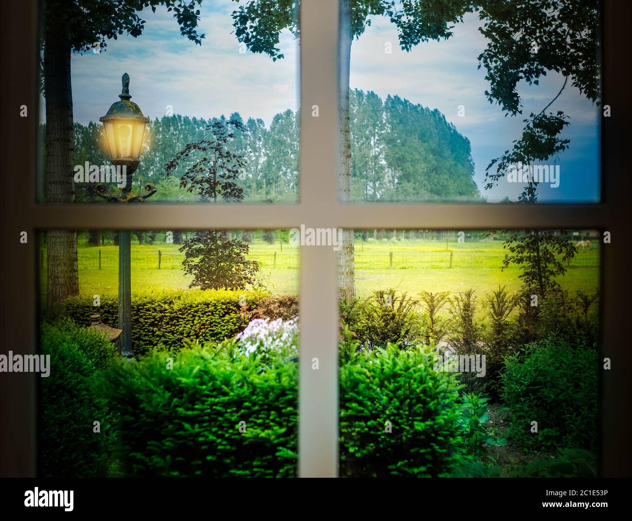 Classic cozy white window and a green forest view with a light in the ...