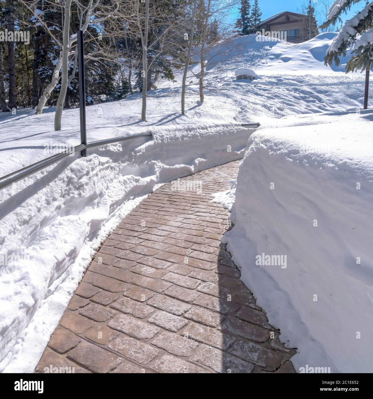 Square Stone brick pathway with metal handrails amid deep layer of snow ...