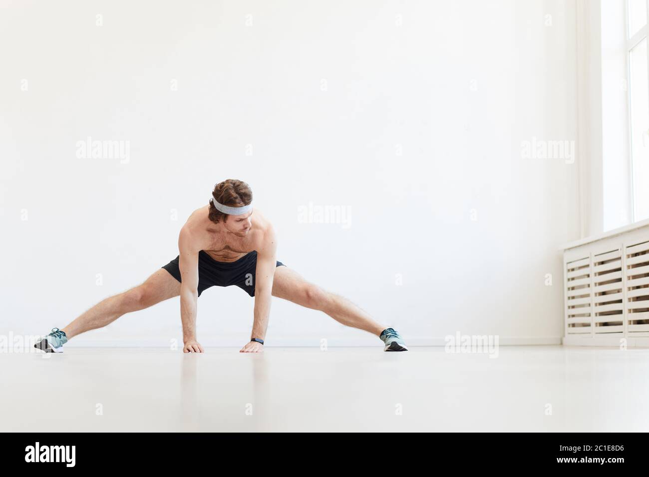 Shirtless muscular man doing stretching exercises during sports ...