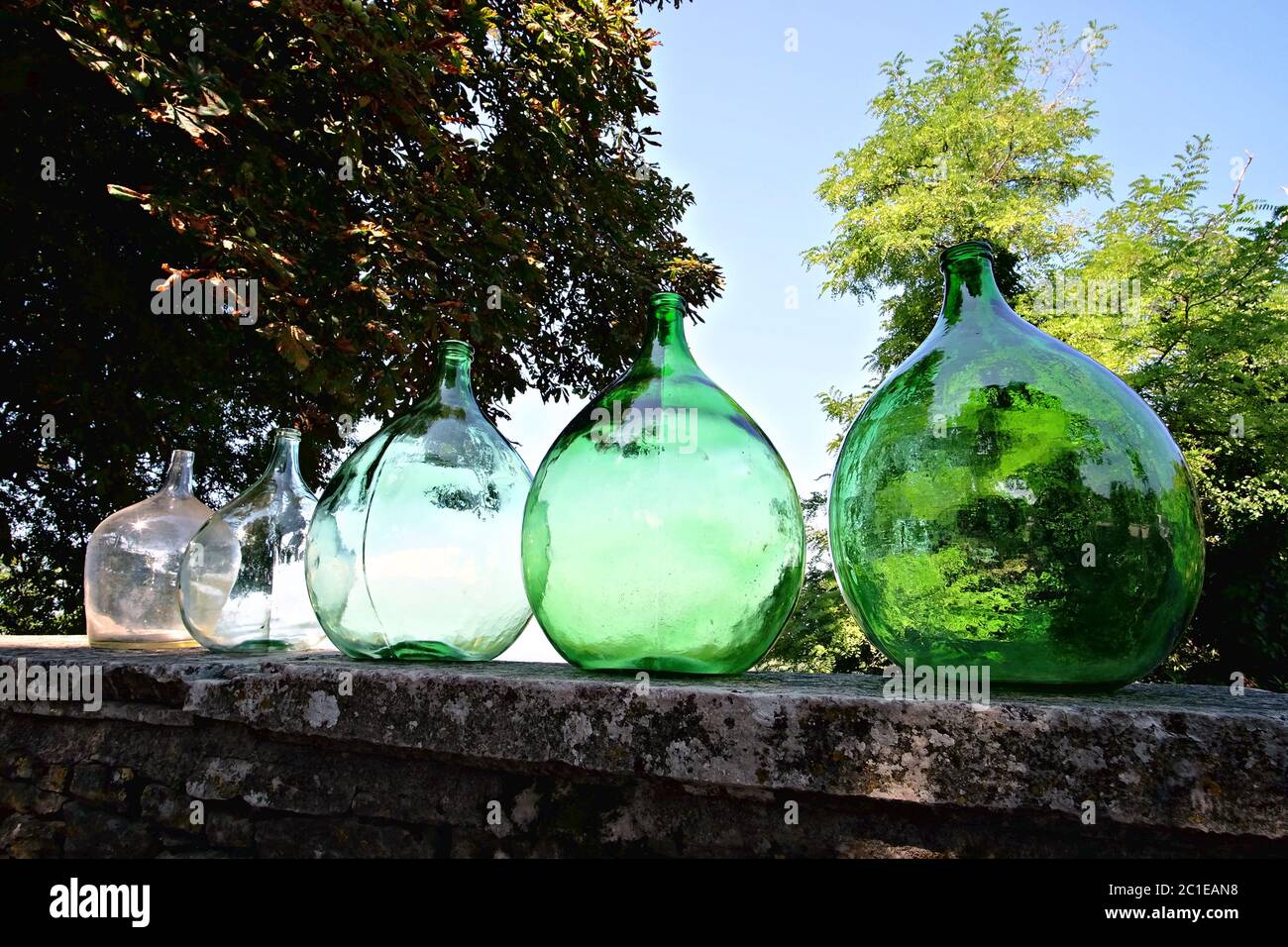 row of vintage glass carboys on a low wall Stock Photo - Alamy