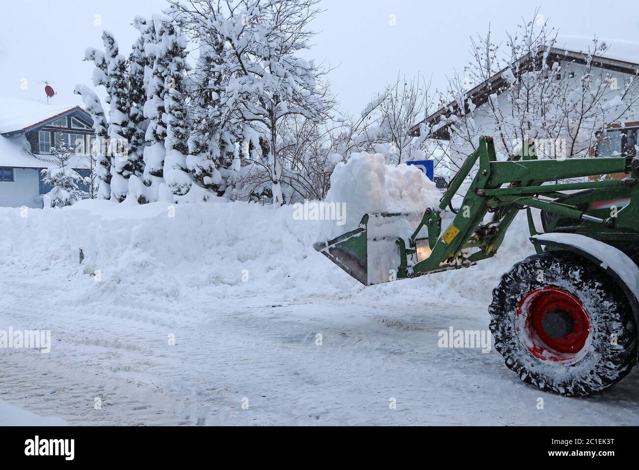 Snow clearing of a road with a tractor. In winter the road in a village ...