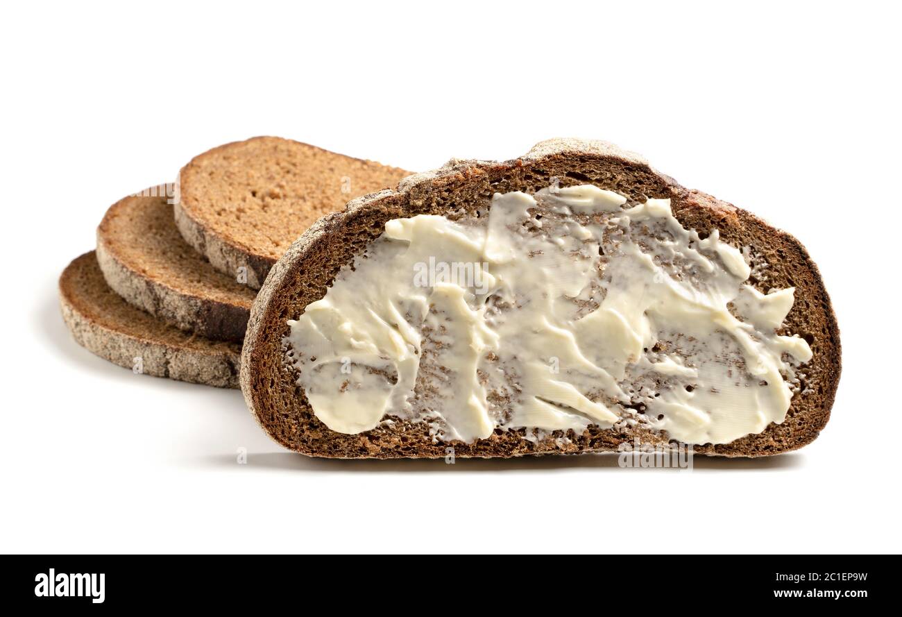 A slice of black rye bread spread with butter on a white background ...