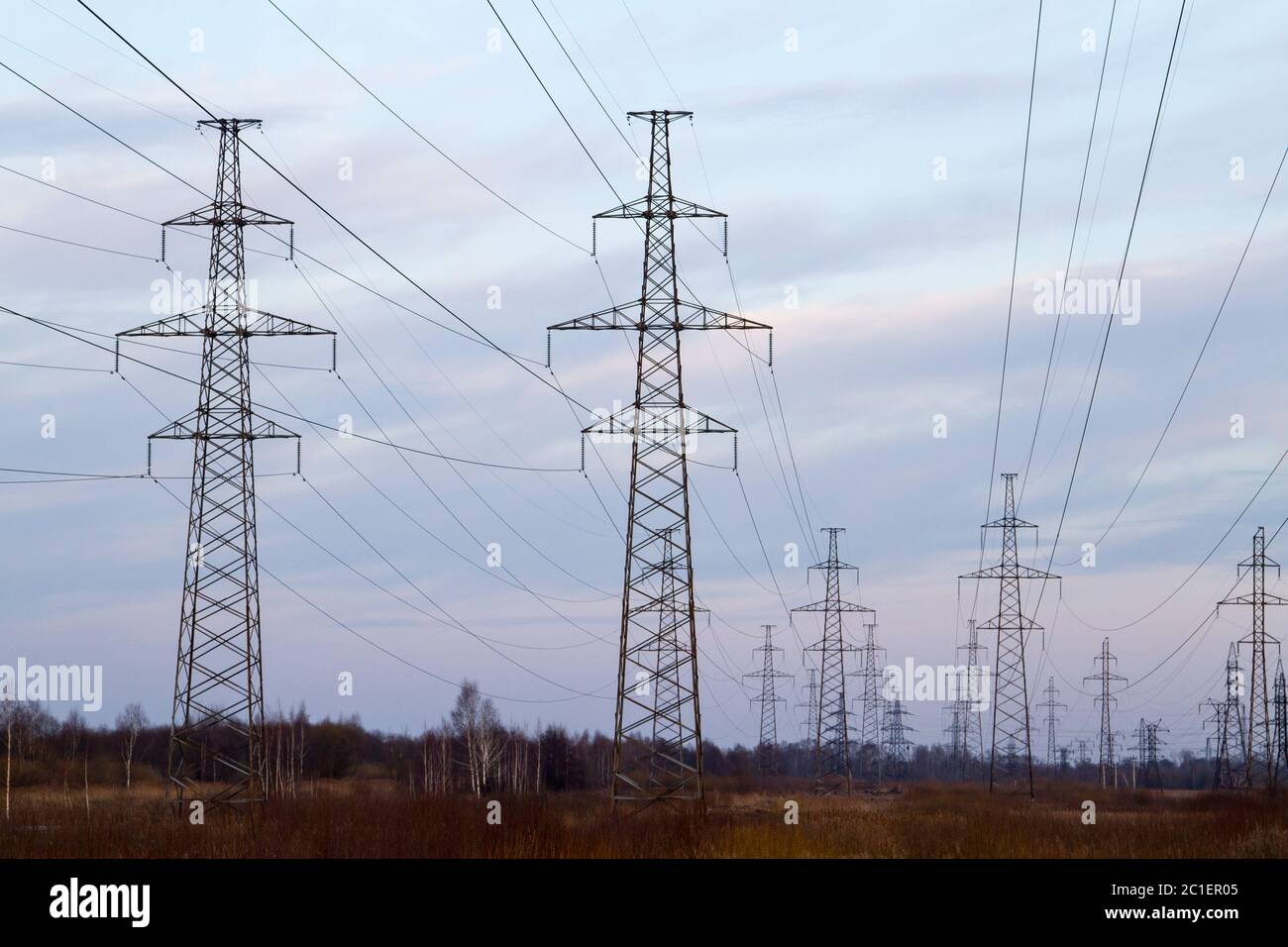 High voltage power lines in the middle of a field at sunset ...