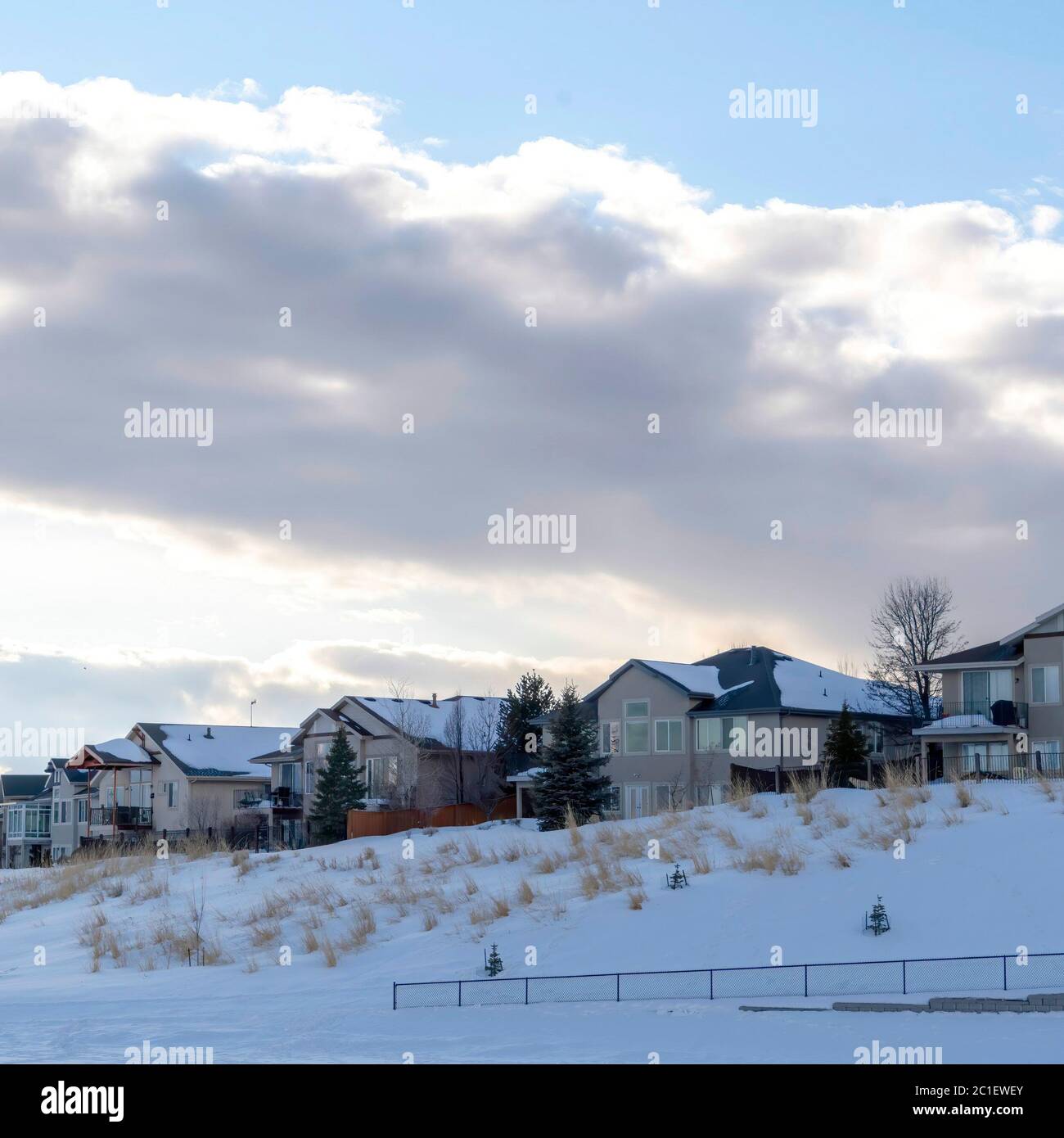 Square crop Clouds and blue sky over homes on pristine terrain of ...