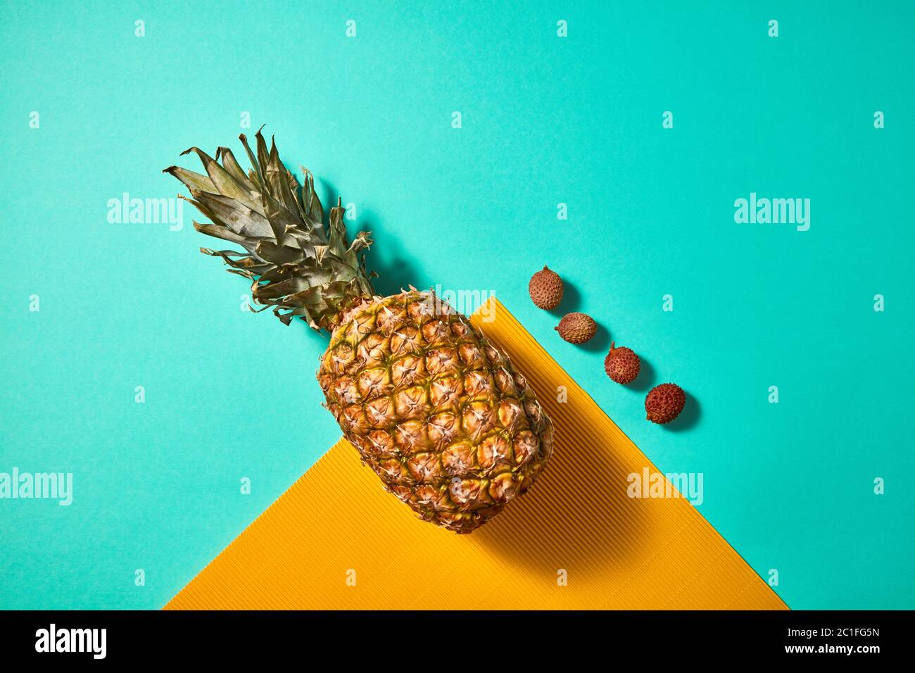 Pineapple and litchi composition on an orange-green background, top ...