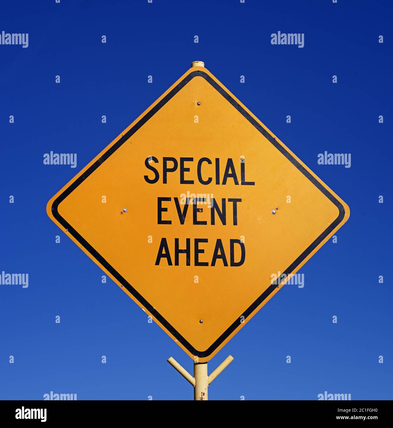 red and yellow special event ahead road sign with blue sky background ...