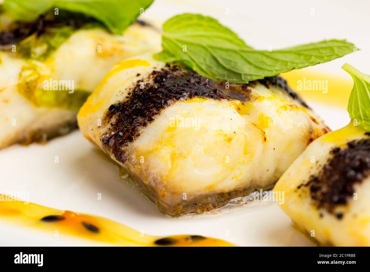 Detail of piece of fish with olive powder, and mint Stock Photo - Alamy