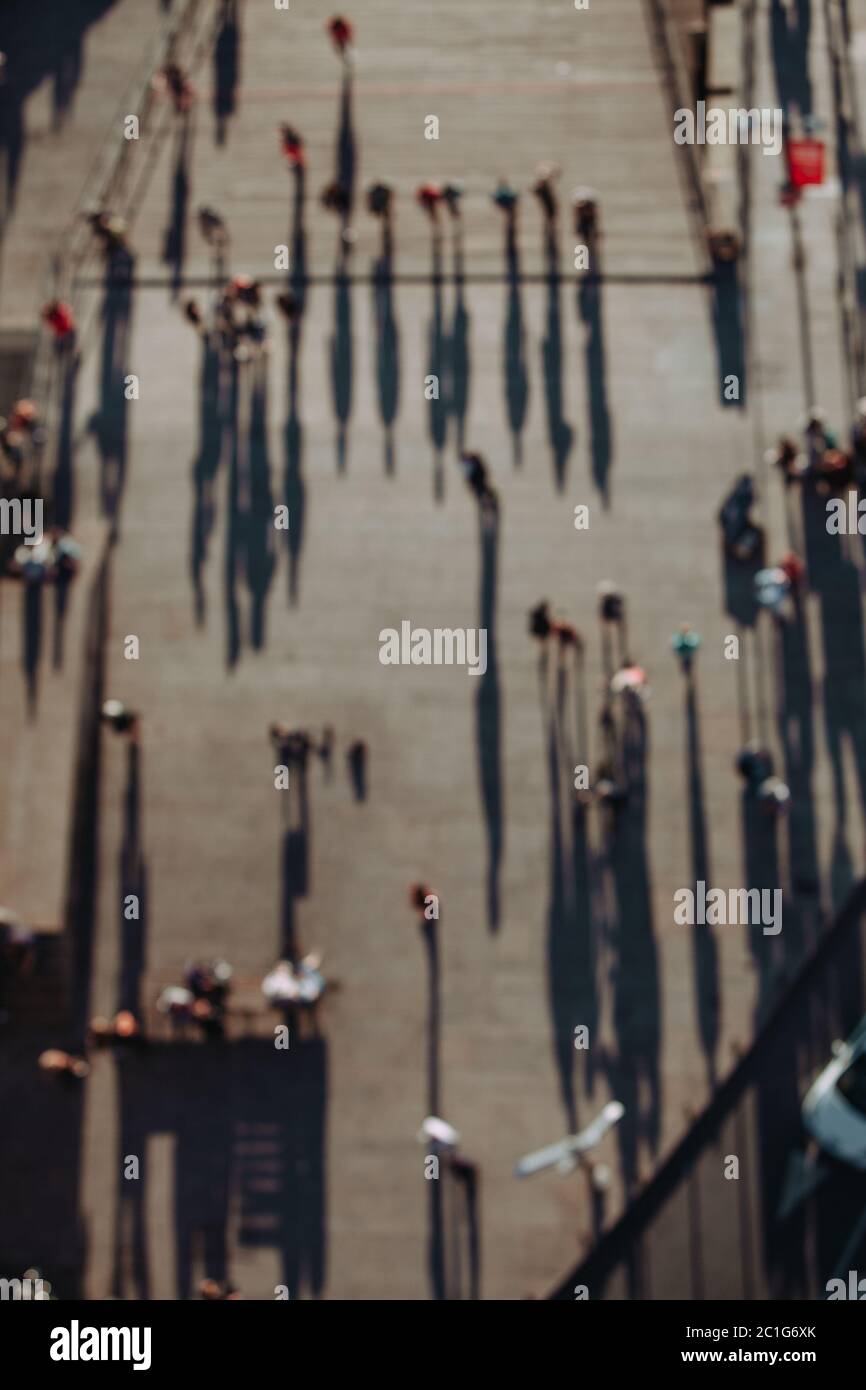 Overhead view of blurred pedestrians walking below, casting long ...