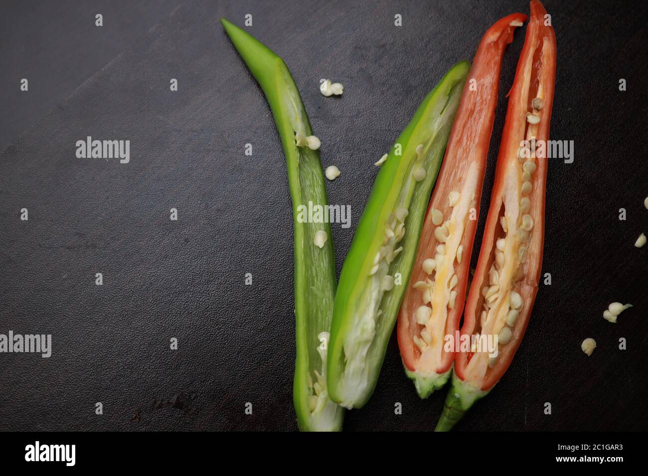Red and Green chilli pepper sliced length-ways on wooden dark board ...