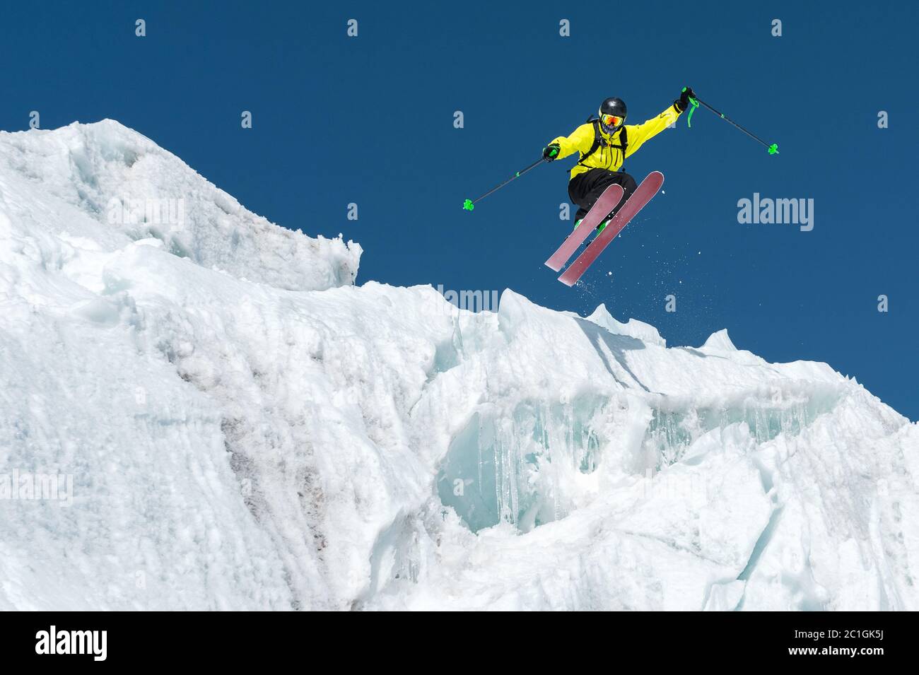 A jumping skier jumping from a glacier against a blue sky high in the ...