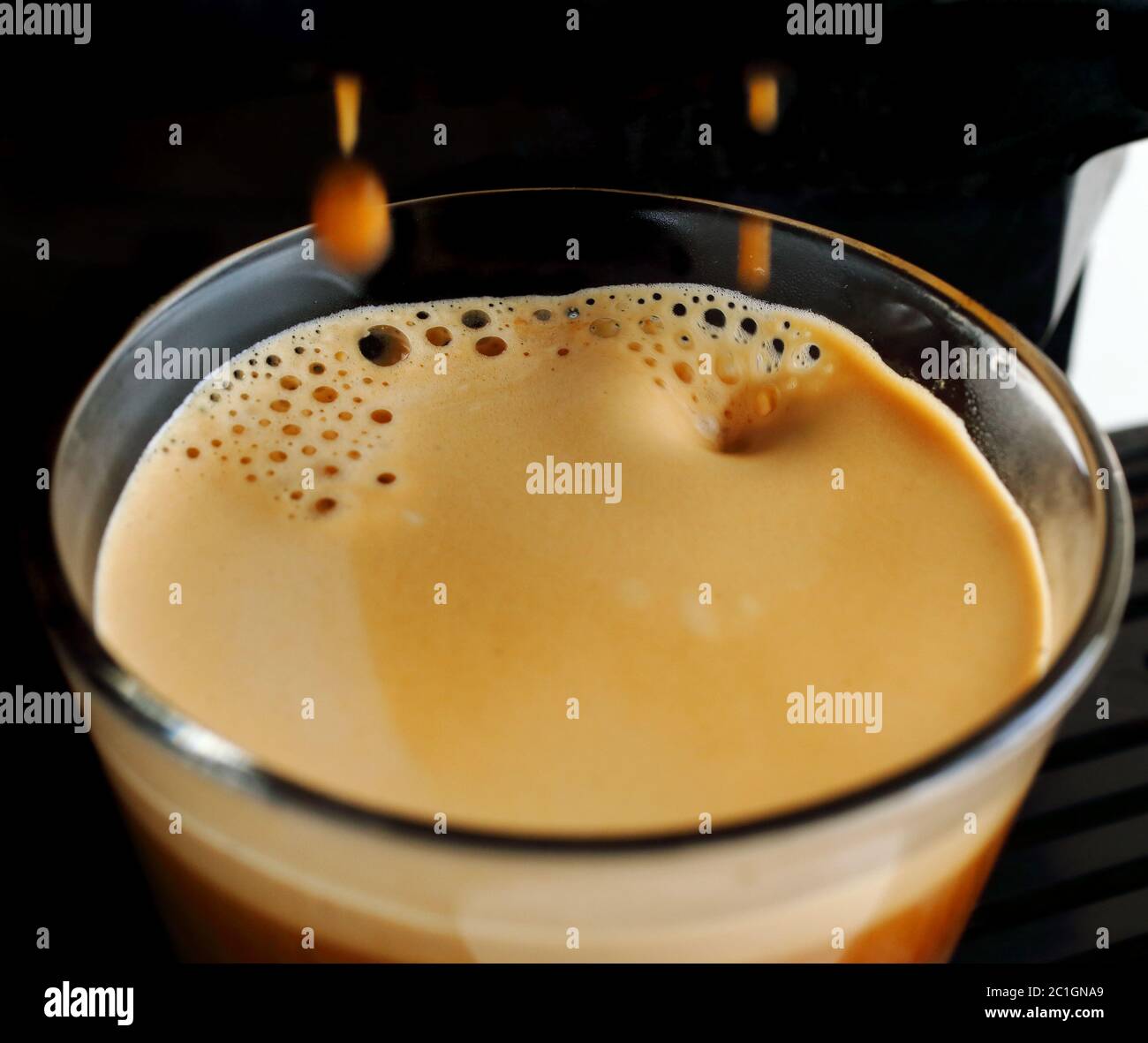 Close-up of fresh espresso coffee, pouring from coffee machine ...