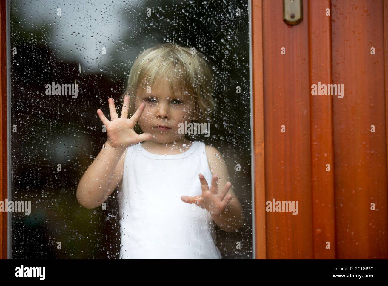 Sad child behind the window on a rainy day Stock Photo - Alamy
