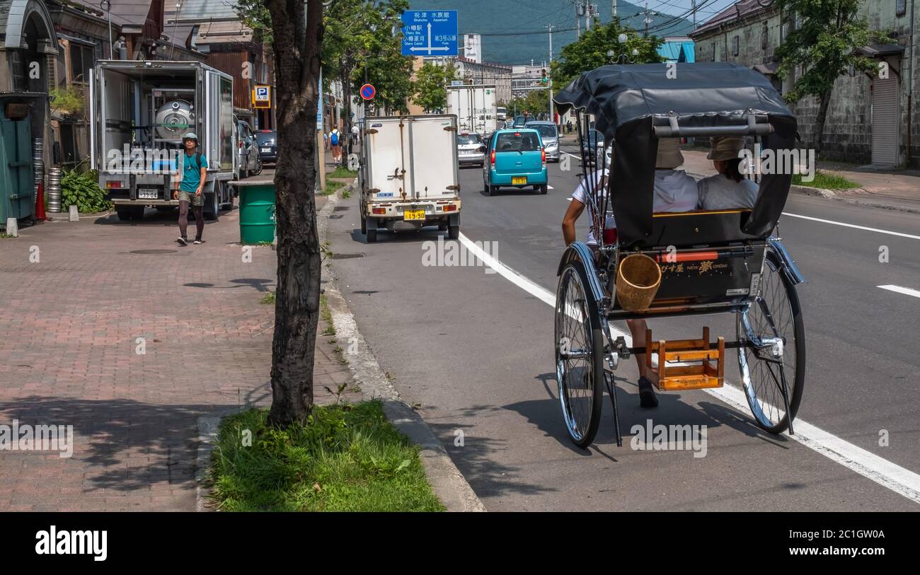 Tourists riding traditional rickshaw in the street of Otaru CIty ...