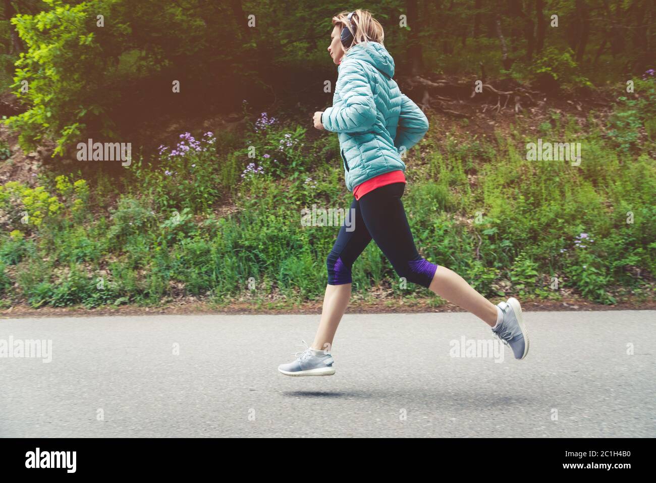 A young blonde woman running is practicing outdoors in a city mountain ...