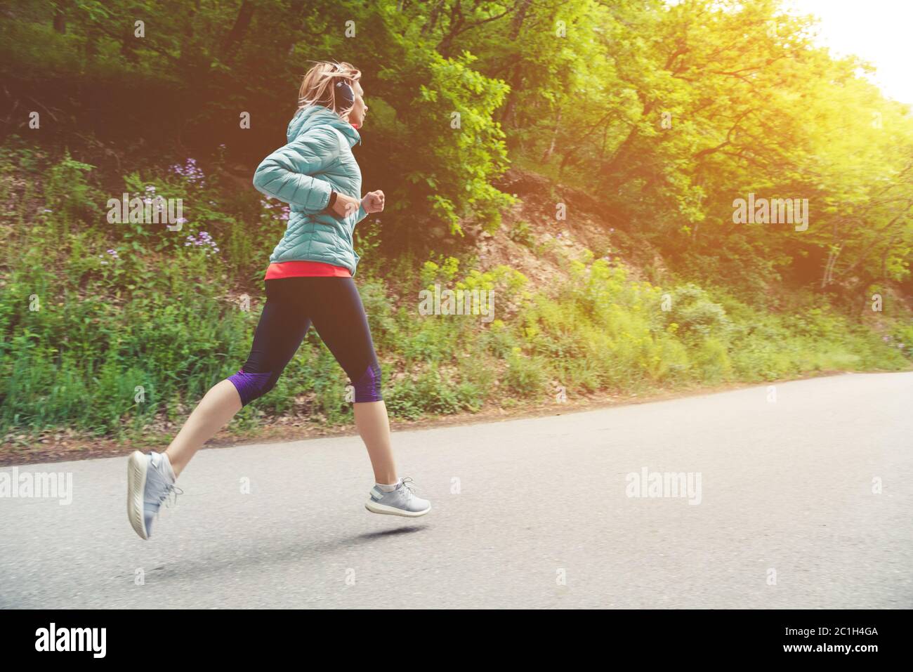 A young blonde woman running is practicing outdoors in a city mountain ...