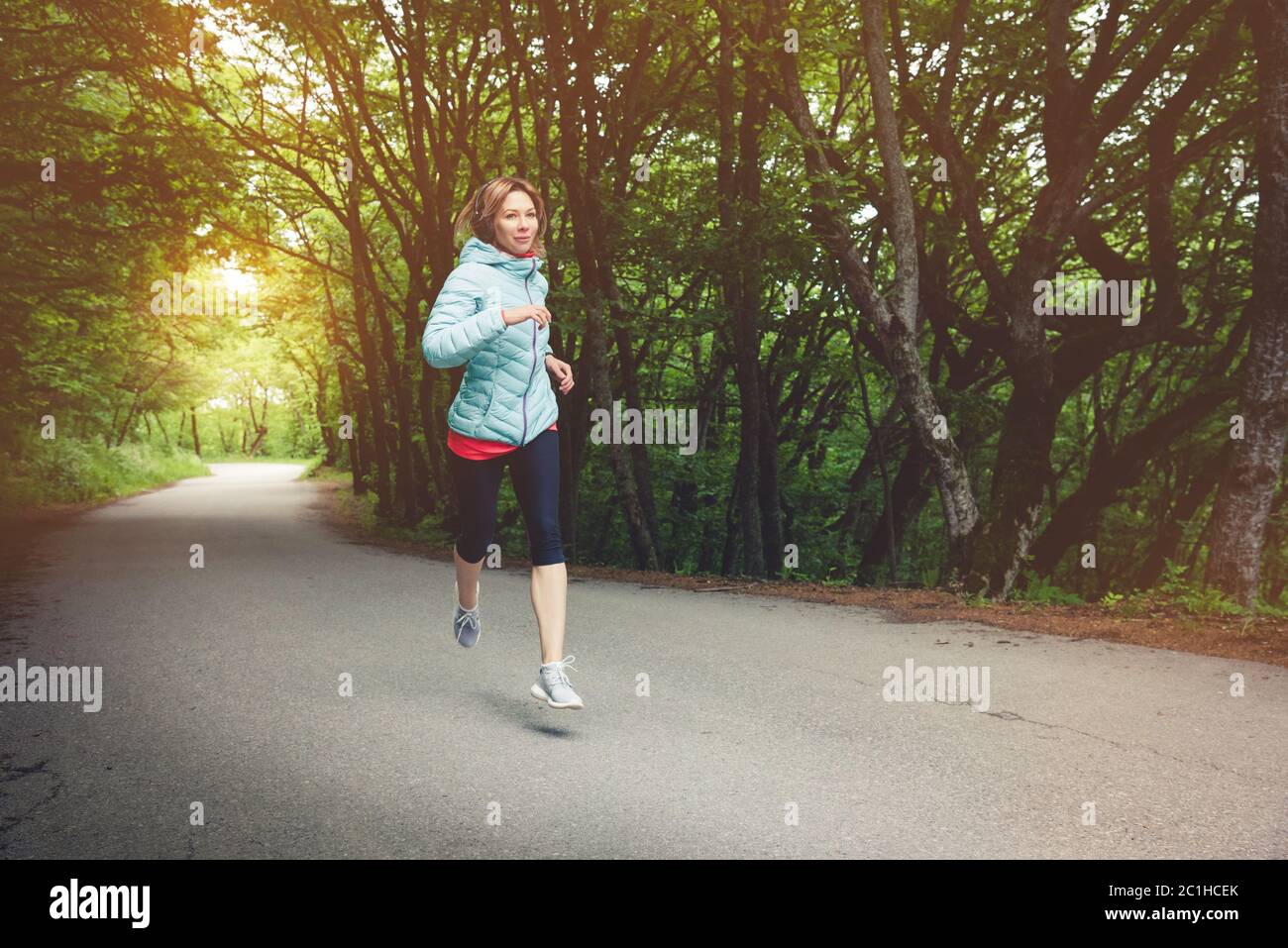 A young blonde woman running is practicing outdoors in a city mountain ...