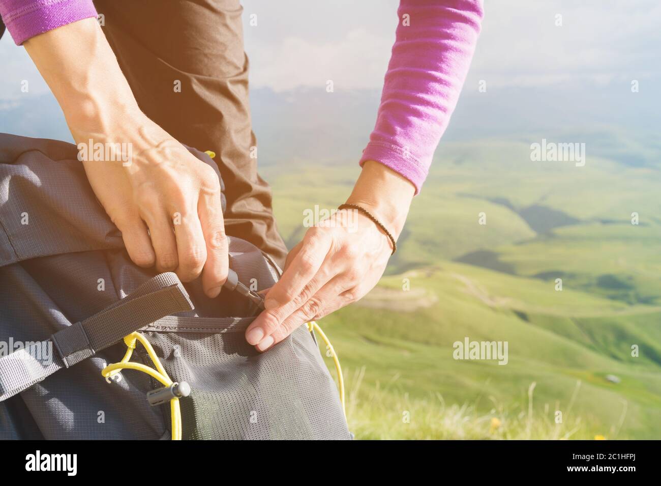 Close-up of women's hands unfasten the buckle on the camp backpack ...