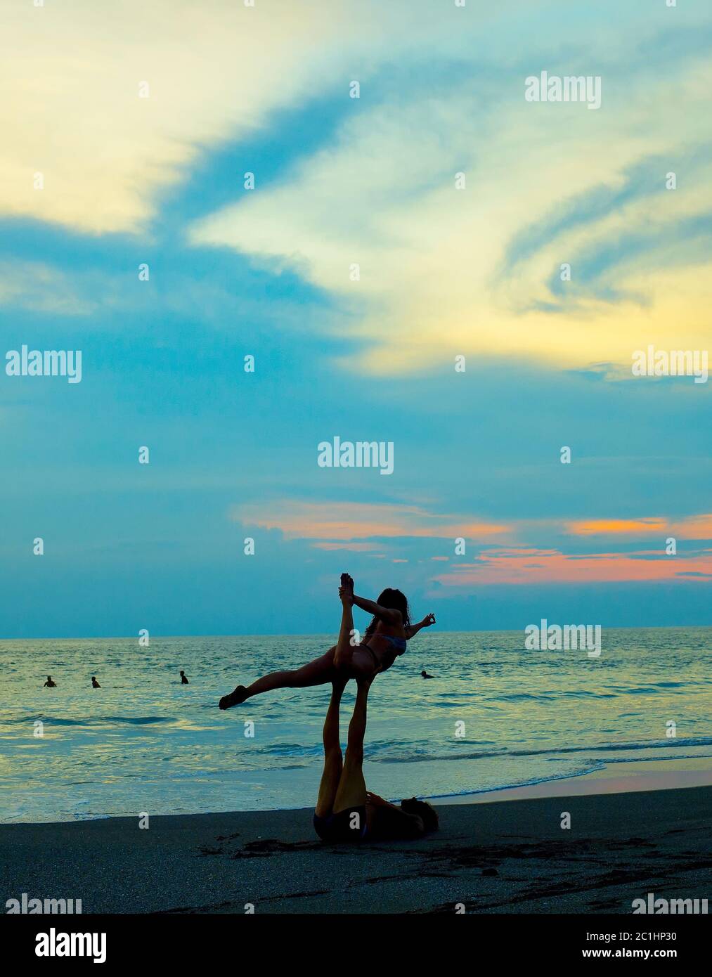 Couple practice yoga at beach Stock Photo - Alamy