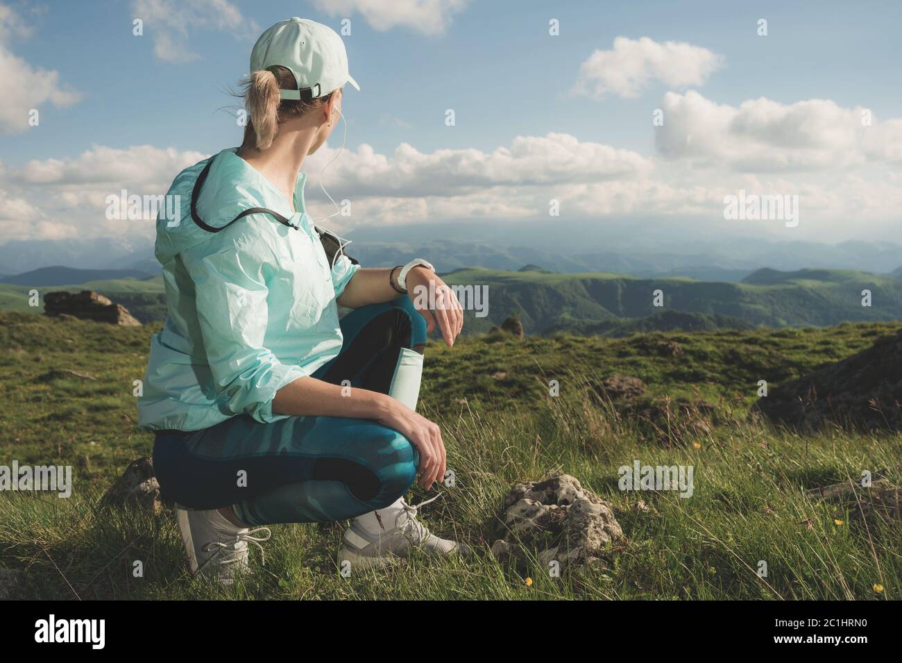 Athlete cute girl in cap with headphones getting ready to run on nature ...