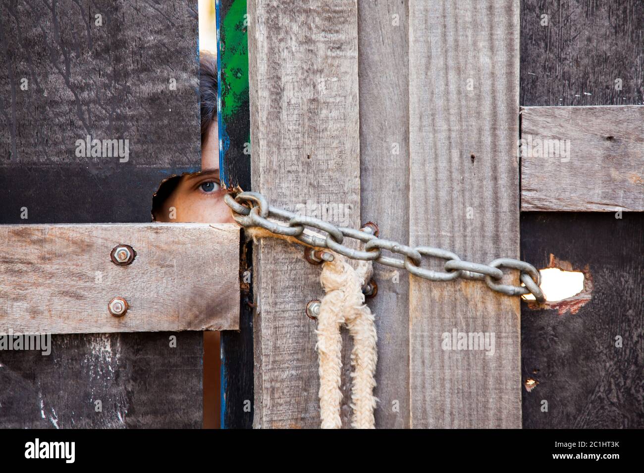 Scared blue eyes behind a locked rustic wood gate with chains Stock ...