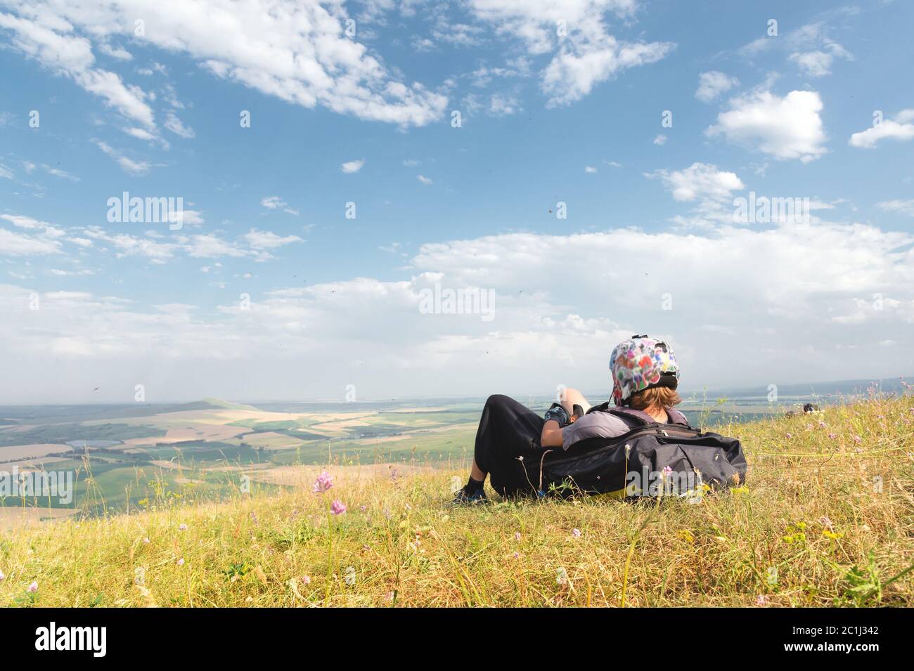 A professional paraglider in full gear and a helmet lies and rests on ...