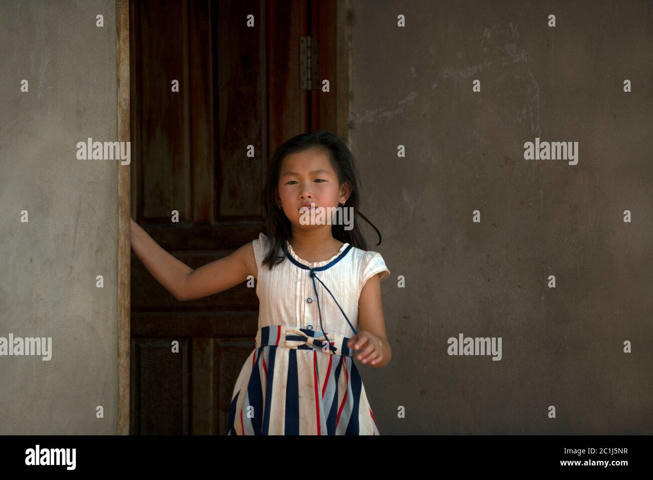A young, indigenous, ethnic Tai Deng girl leaving her house in her ...