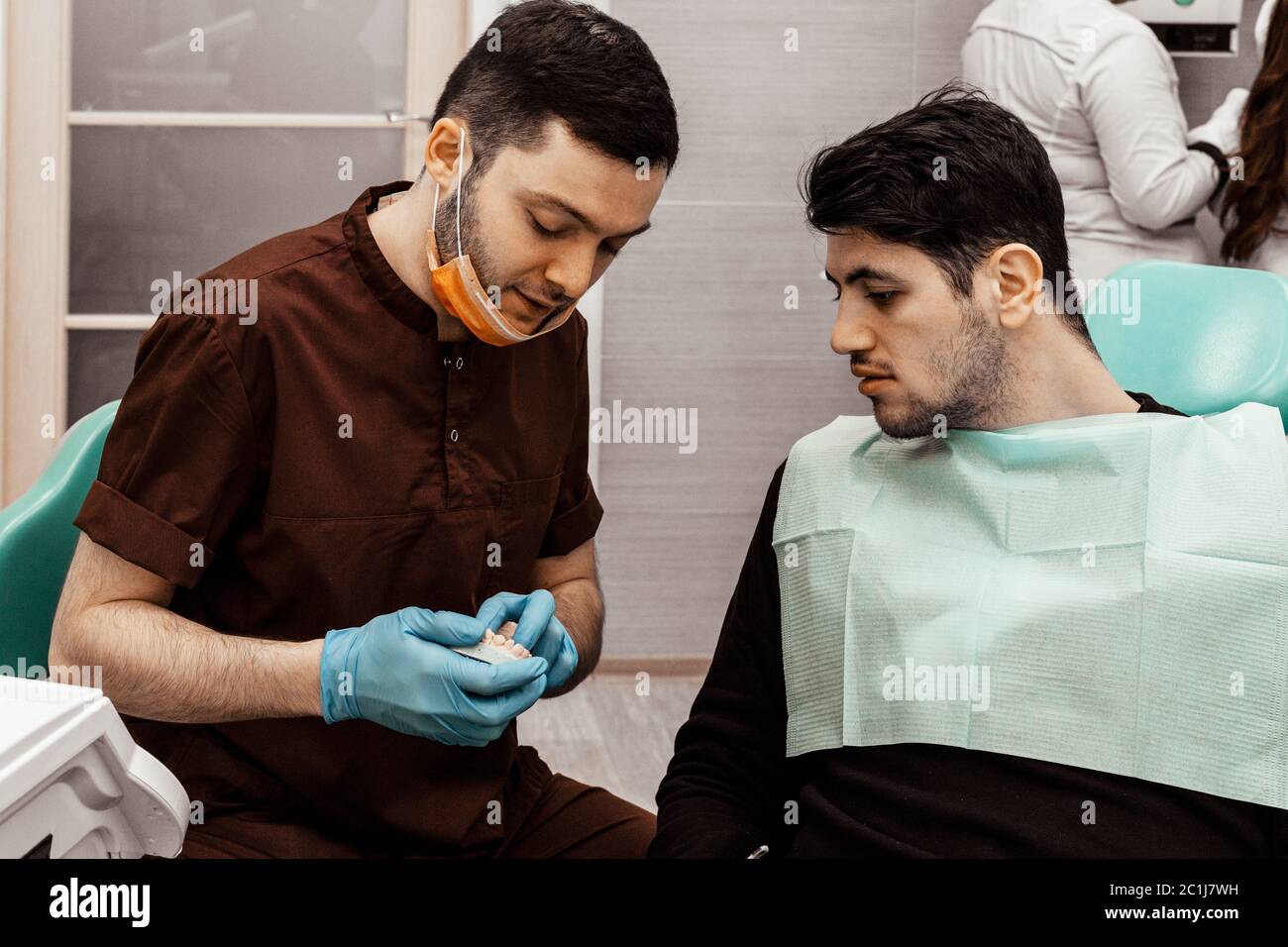A young dentist discusses a diagnosis and treatment plan with a patient ...