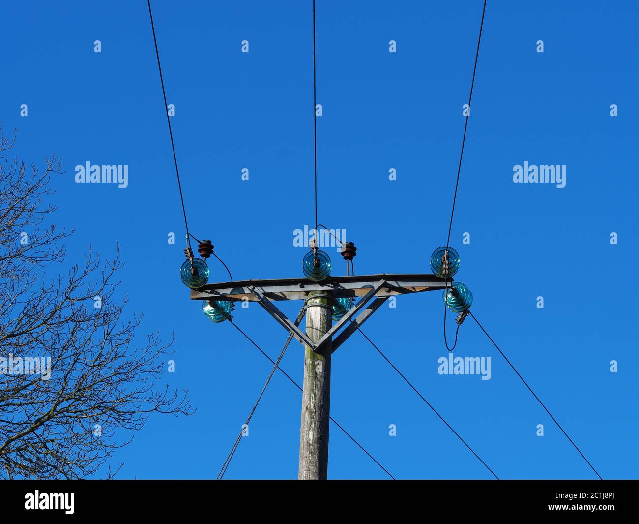 Overhead electric power lines with glass insulators and a clear blue ...
