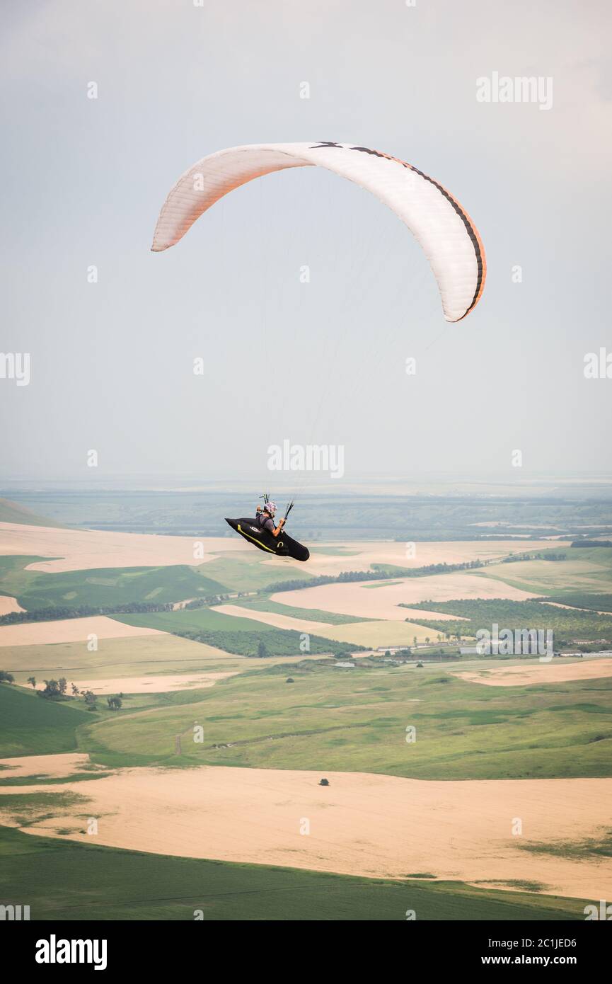 White orange paraglide with a paraglider in a cocoon against the ...