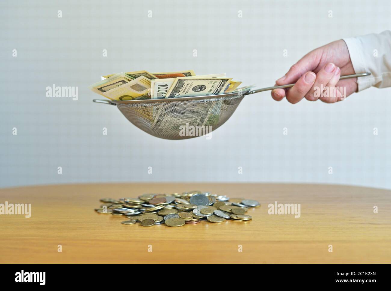 sift money through a sieve. coins fall out of the sieve Stock Photo - Alamy