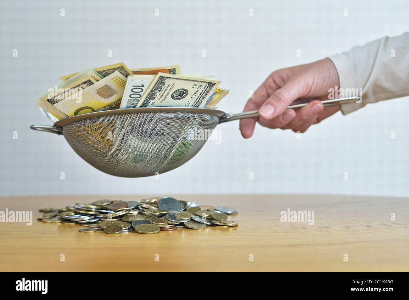 sift money through a sieve. coins fall out of the sieve Stock Photo - Alamy