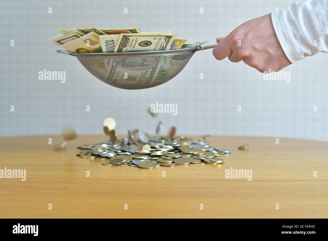 sift money through a sieve. coins fall out of the sieve Stock Photo - Alamy