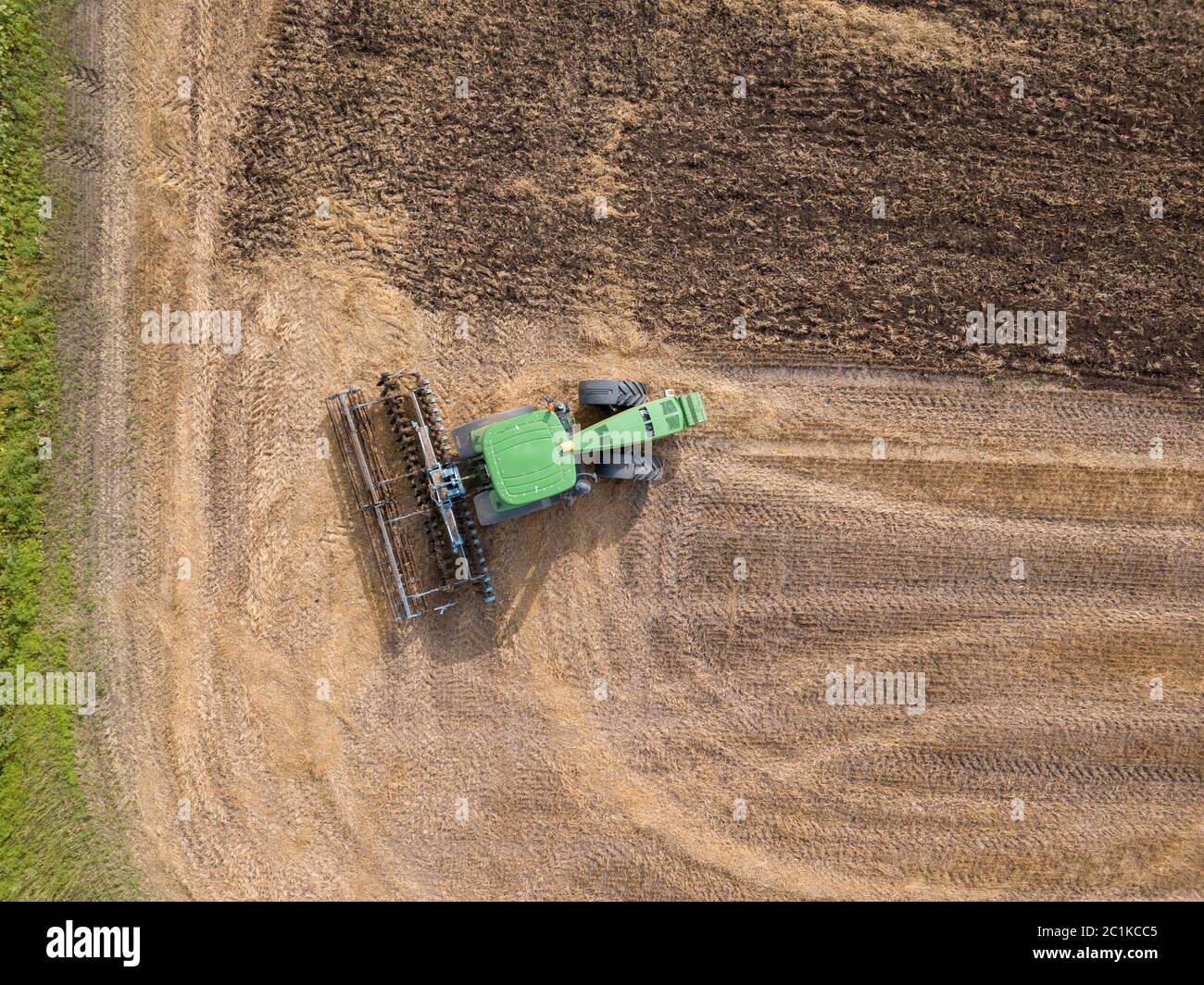 Top view of green tractor plowing the ground after harvesting on the ...