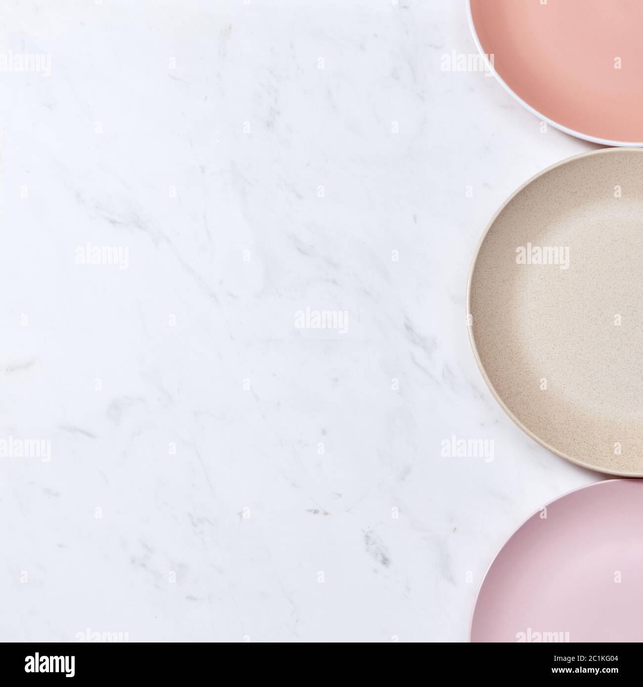 Corner frame with porcelain empty plates on a gray marble table. Pastel ...
