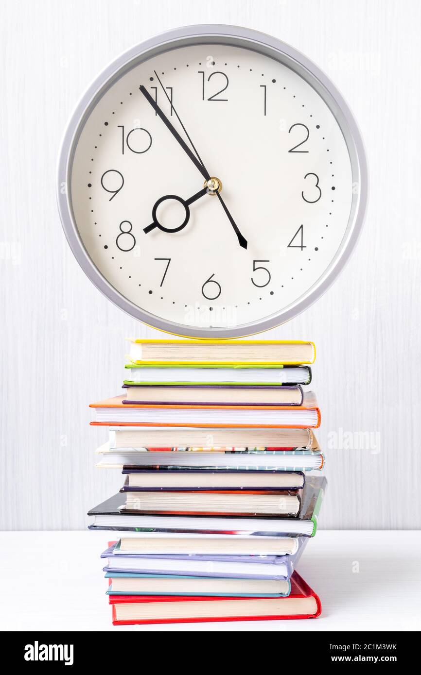 Wall clock and stack of books Stock Photo - Alamy