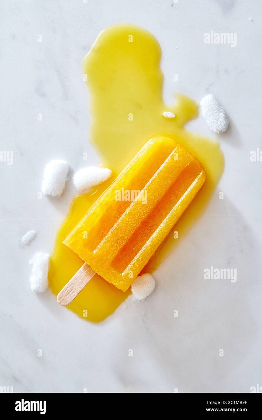 Yellow Icecream lolly pop over marble light background with ice and ...