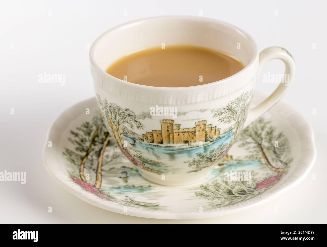 Teacup with tea and saucer decorated with English castle scene ...