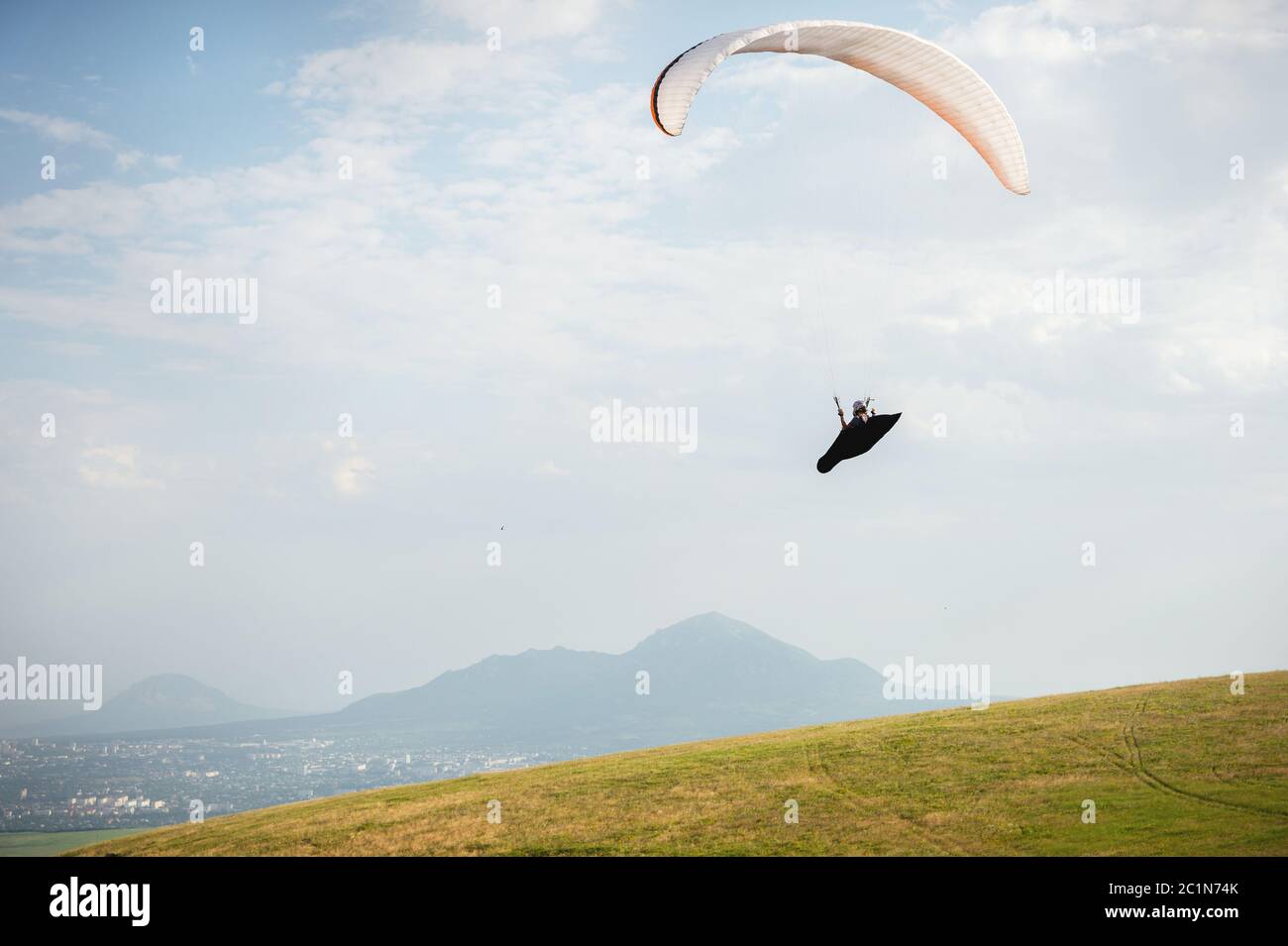 A white-orange paraglider flies over the mountainous terrain Stock ...