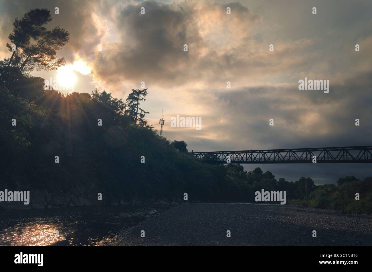 Town/City landscape at sunset with bridge to train station by river bed ...