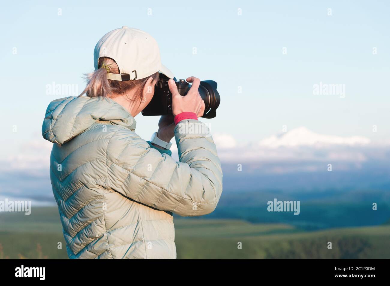 Portrait of a girl photographer in a cap on nature photographing on her ...